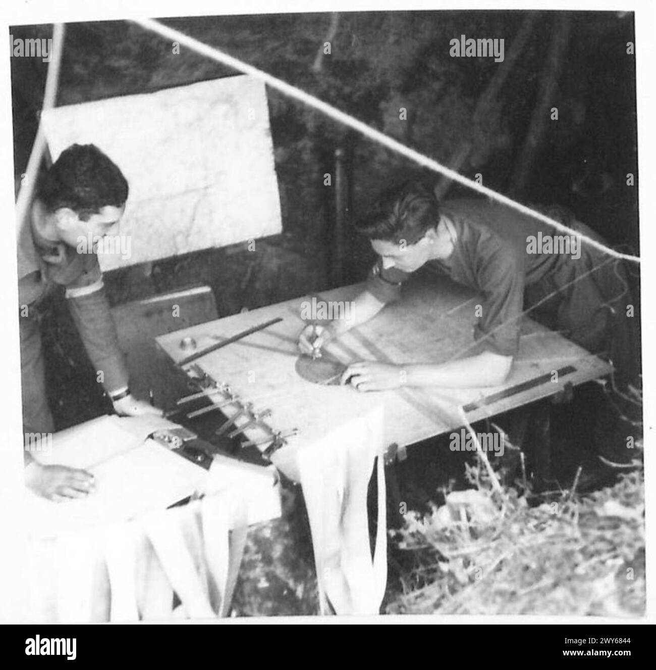 A ROYAL ARTILLERY BATTERY IN ACTION - The plotter at work on his maps ...