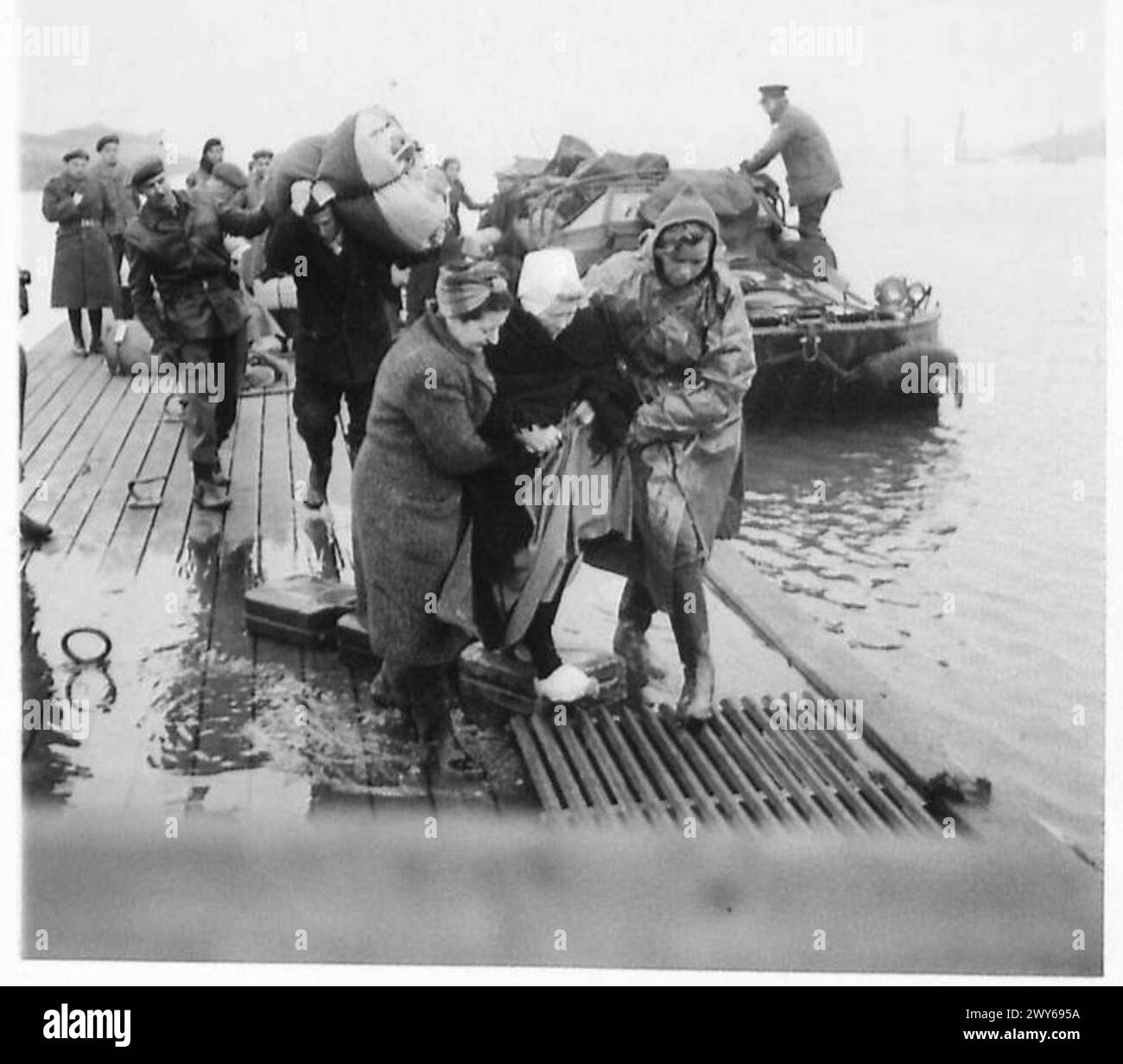 Dutch Red Cross workers assist an elderly lady ashore from amphibious ...