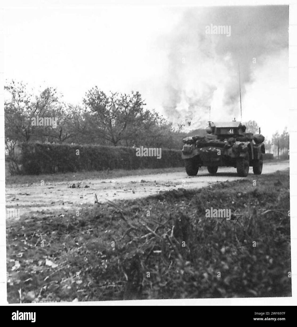 A Reece scout car is seen passing a burning house during operations ...
