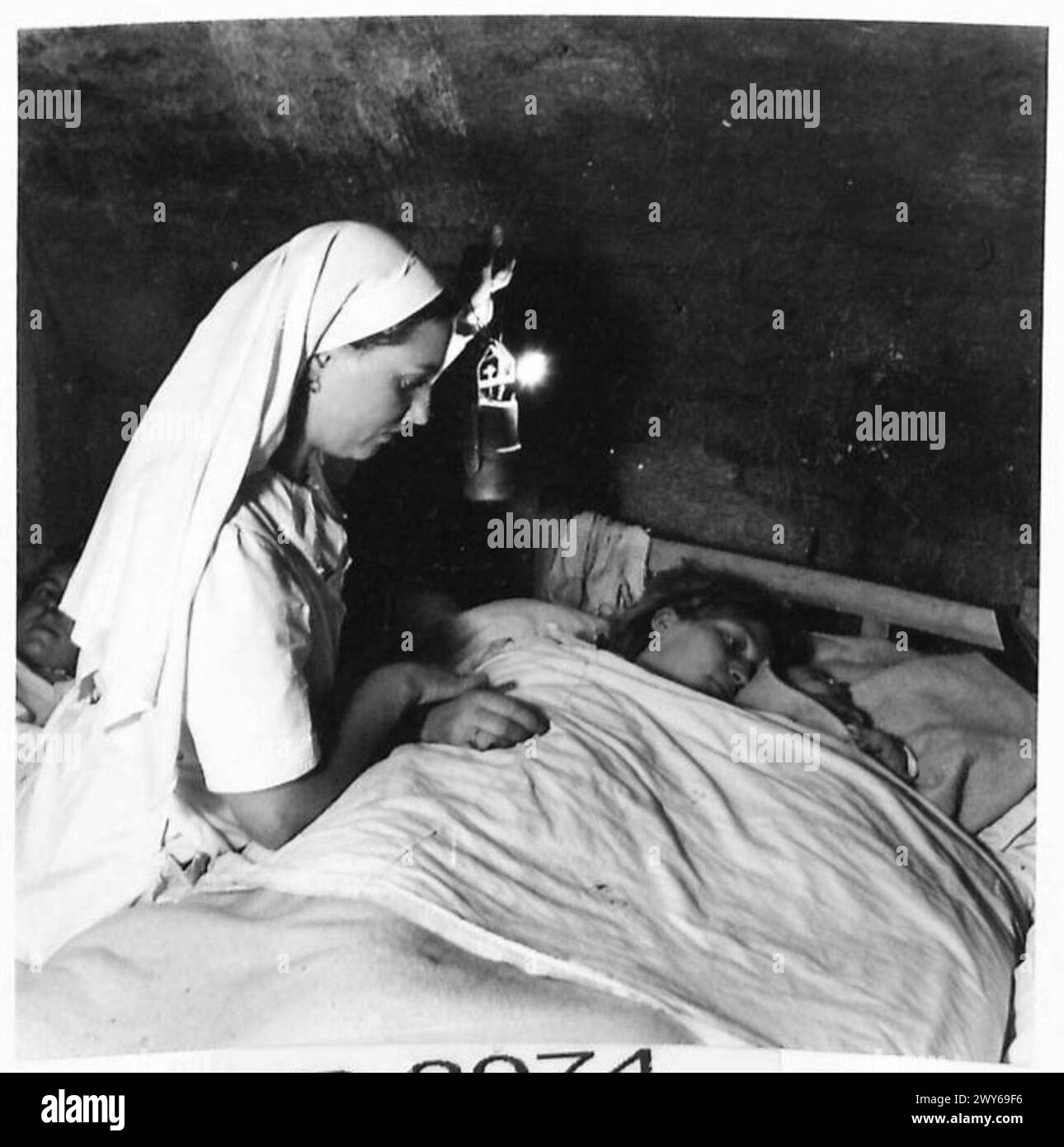 BENOUVILLE MATERNITY HOME - By the light of an acetylene lamp a nurse ...