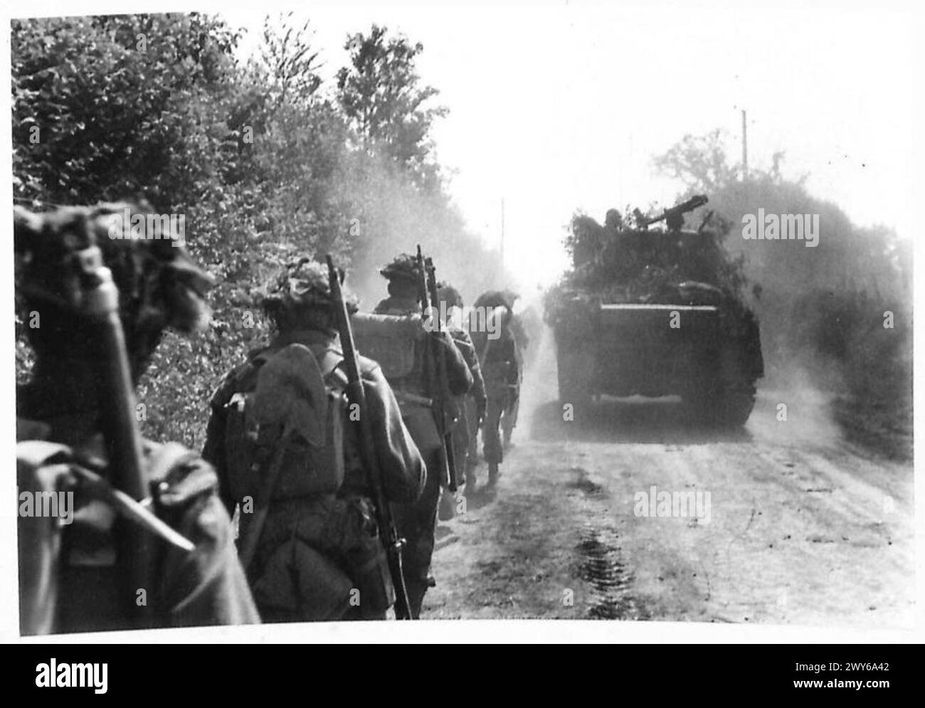 Men of the Irish Guards advance with tanks along a road near St. Martin ...