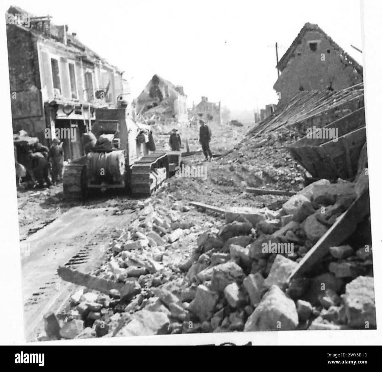 An armoured bulldozer clears a road through bomb craters and rubble on ...