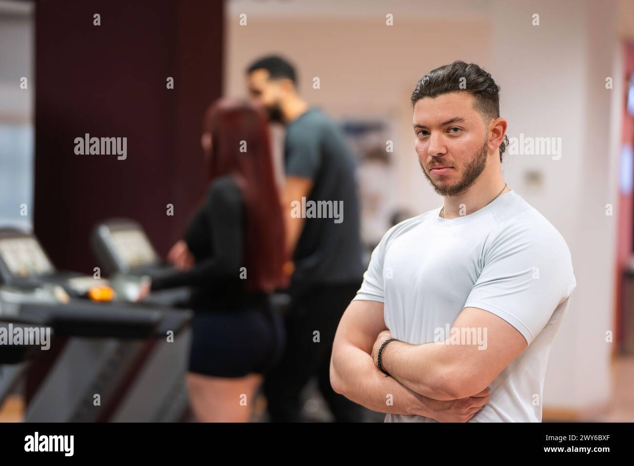 Serious men looking gym goer standing with arms crossed in a ...
