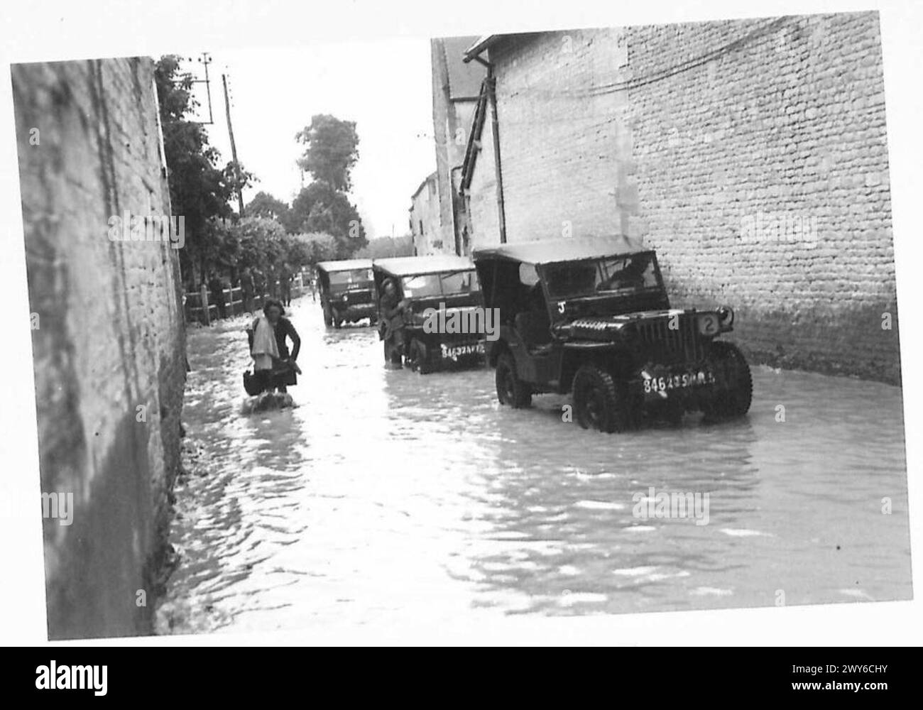 Flooded roads in Cully, Normandy, show British Army vehicles moving ...