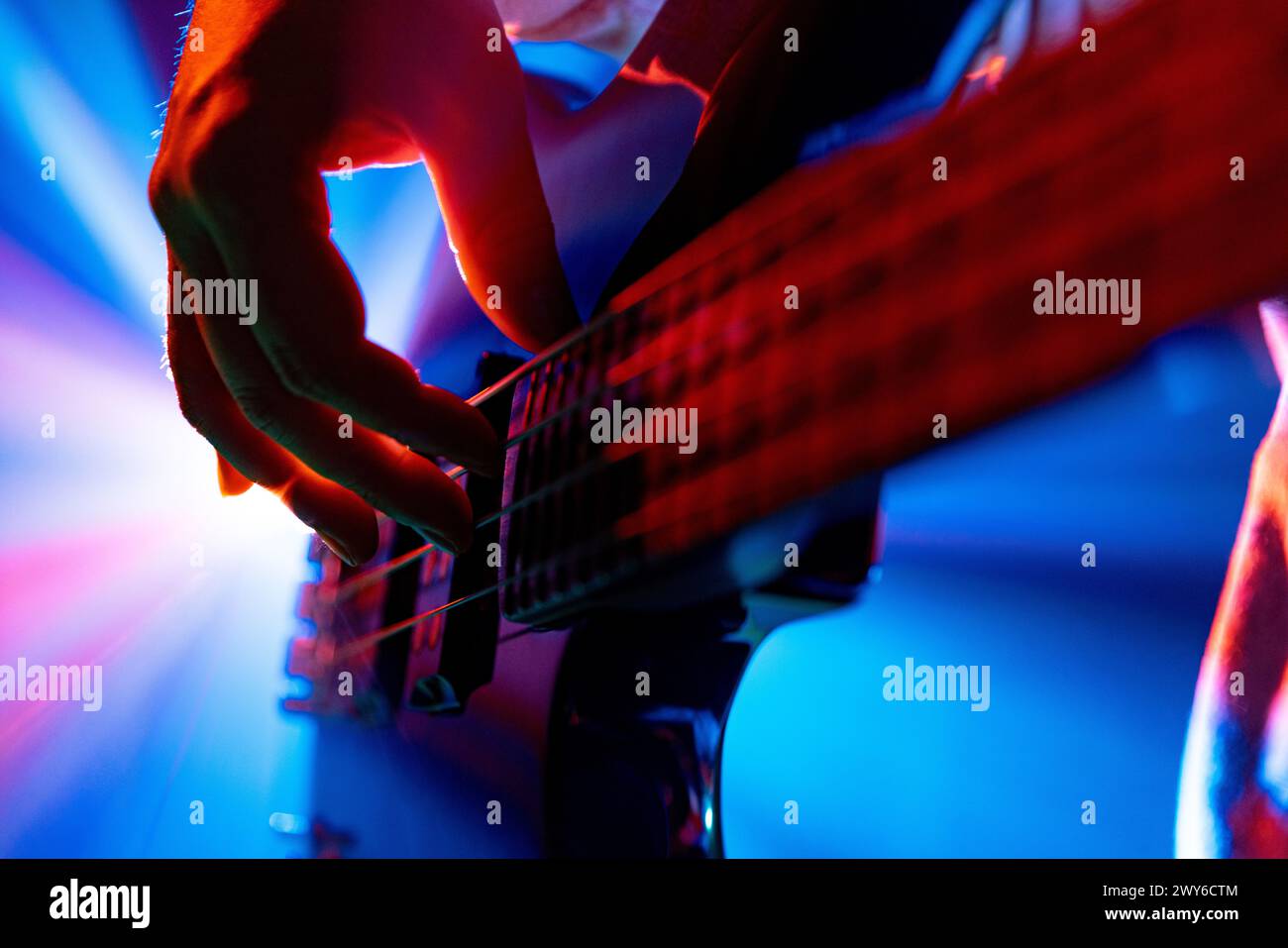 Guitarist's hands plucking strings of bass, electric guitar with ...