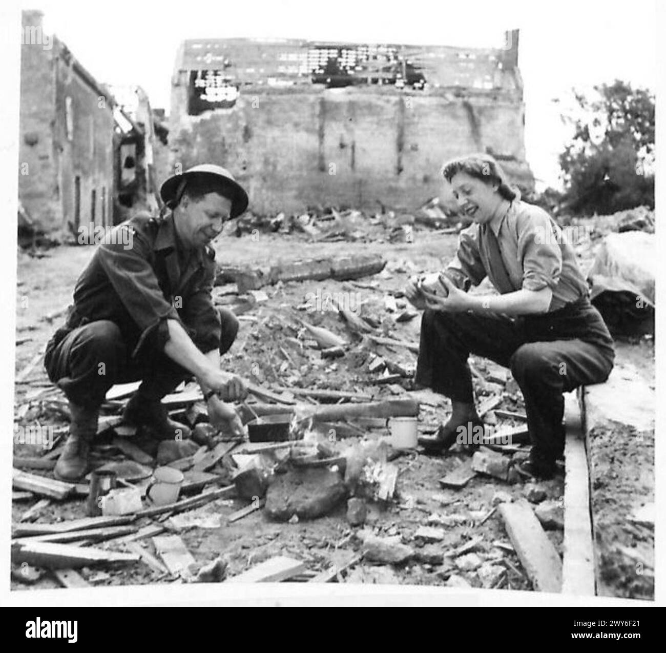 GEORGE FORMBY IN NORMANDY - George Formby and his wife Beryl cooking a meal in the ruins of a ...