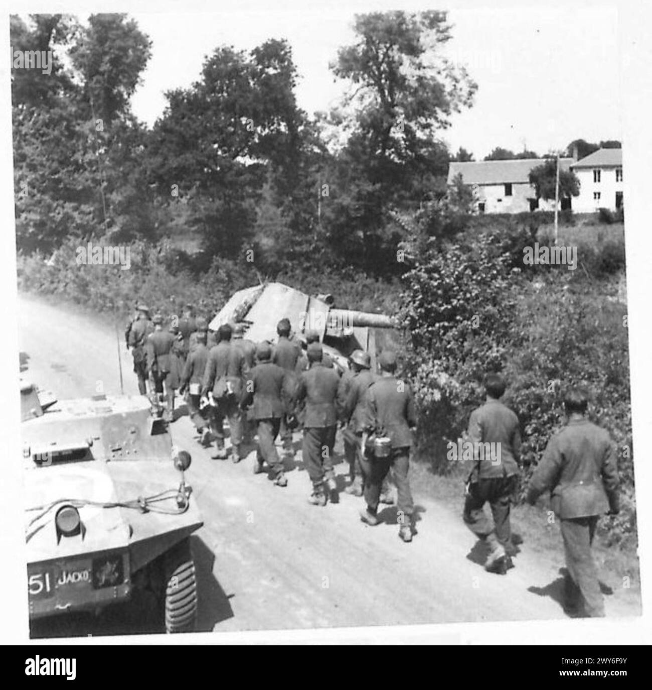 Prisoners captured during the attack south of Aunay-sur-Odon pass a destroyed German self ...