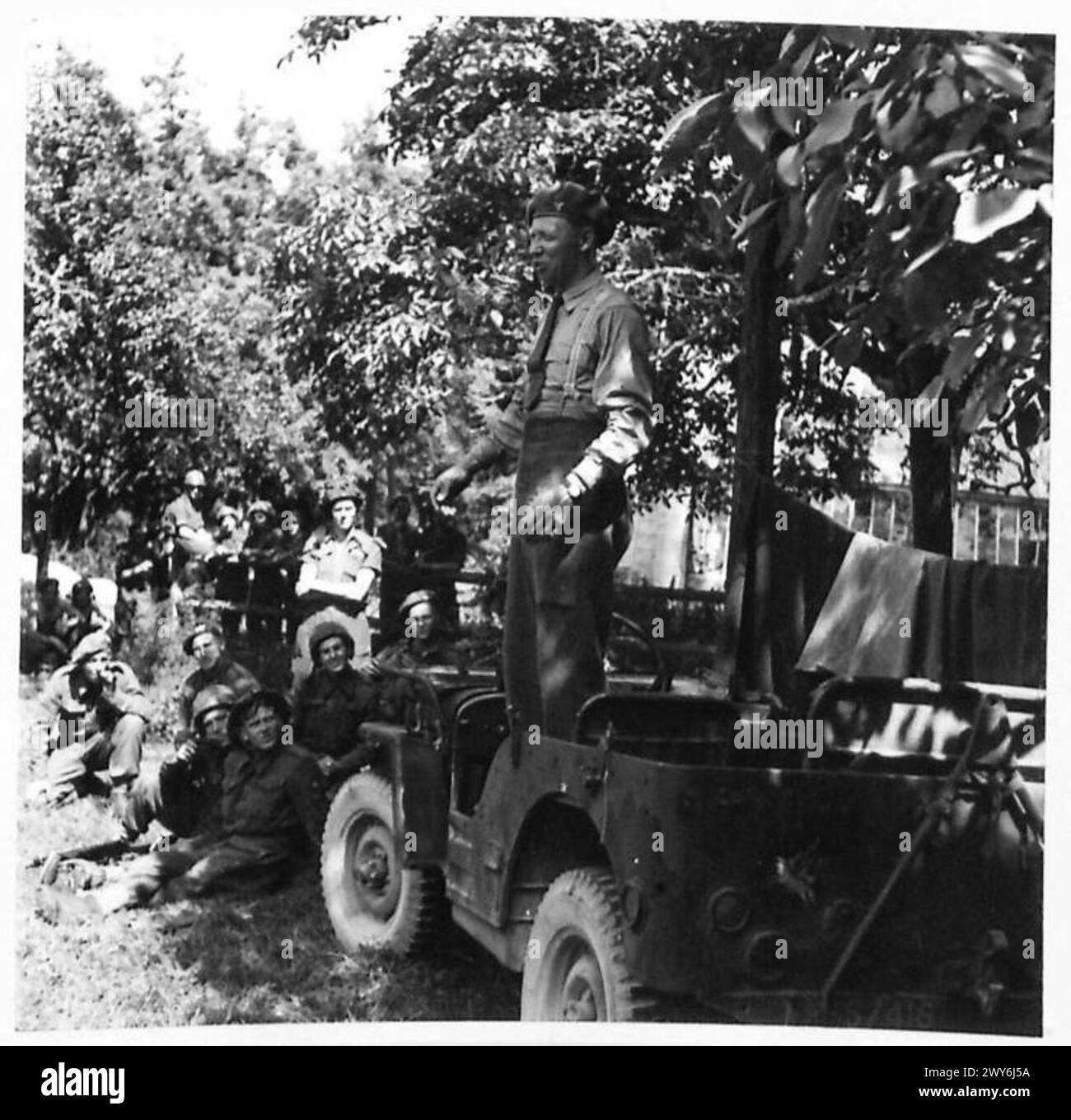 GEORGE FORMBY ENTERTAINED TROOPS IN NORMANDY - George Formby standing on a jeep entertaining the ...