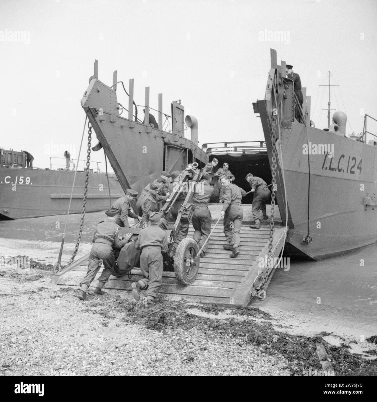 A 3.7-inch Howitzer is loaded aboard a tank landing craft during a ...