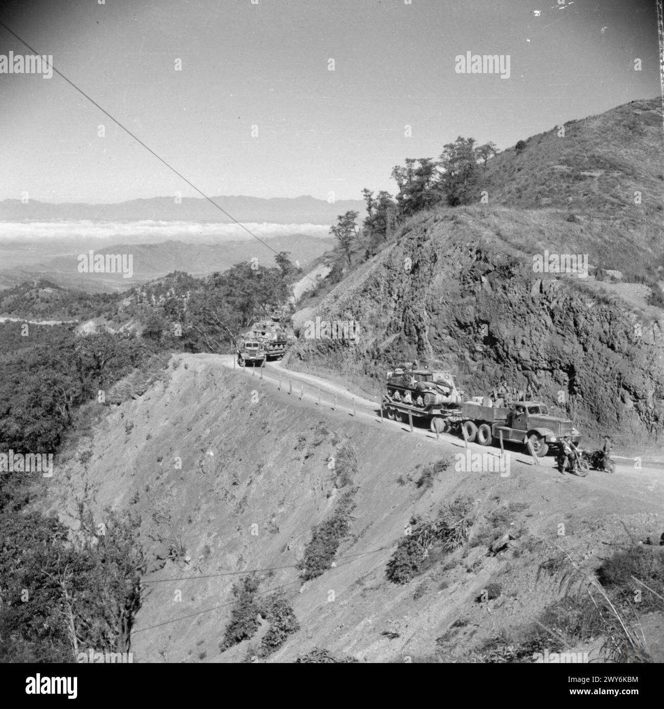 A Diamond T tank transporter carries a Grant ARV along the road to Tamu ...