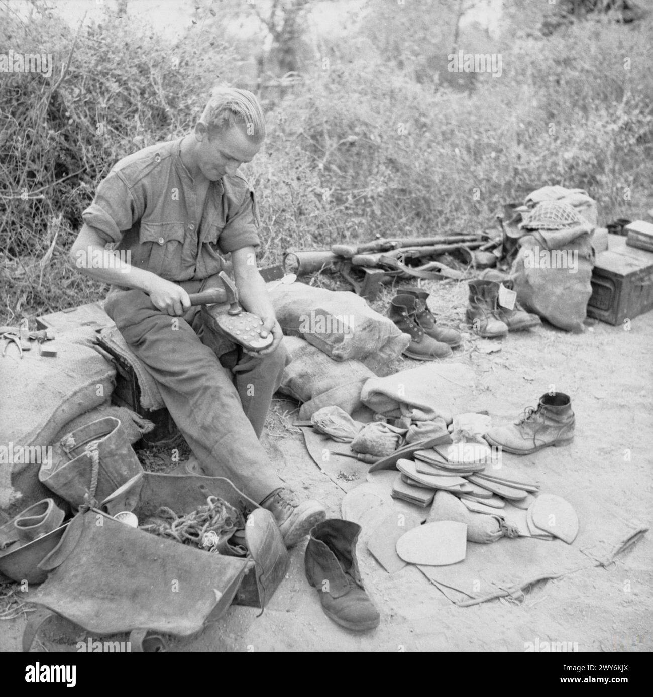 A soldier of the 20th Division mends boots as a cobbler after capturing ...