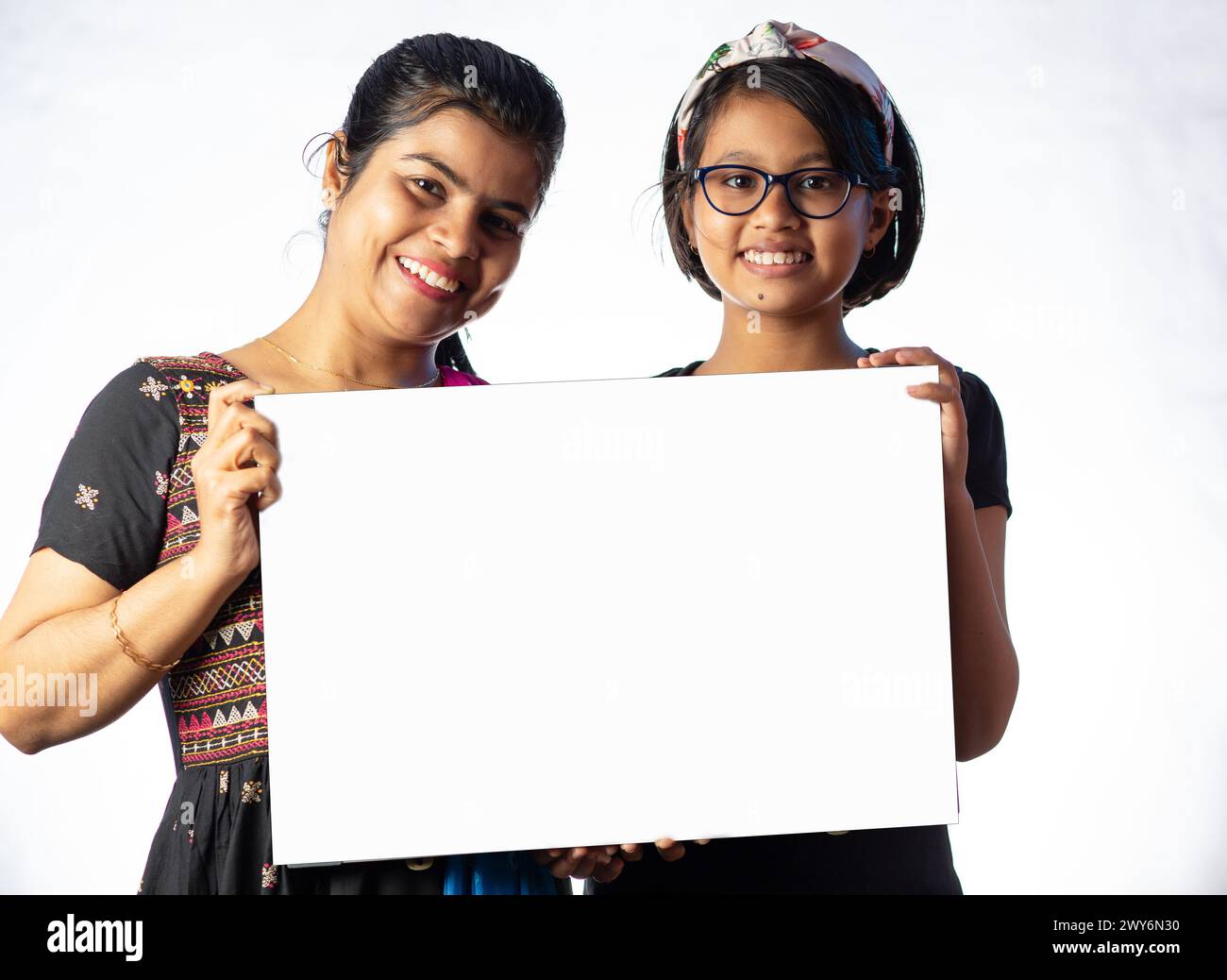 An Indian pretty girl child smiling and showing white blank placard ...