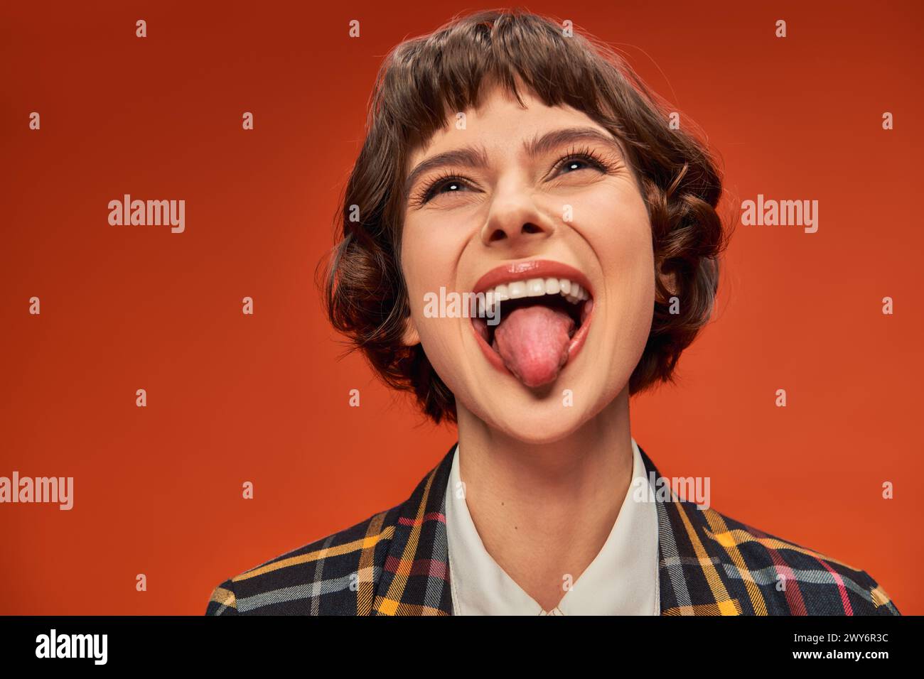 Playful female student in college uniform sticking out tongue, lively ...