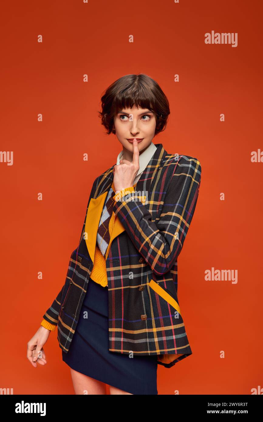 student with short hair posing in stylish checkered blazer on orange ...