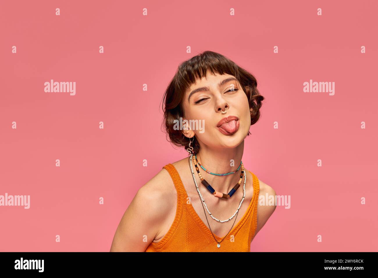 cheeky carefree girl in 20s with short brunette hair sticking tongue ...