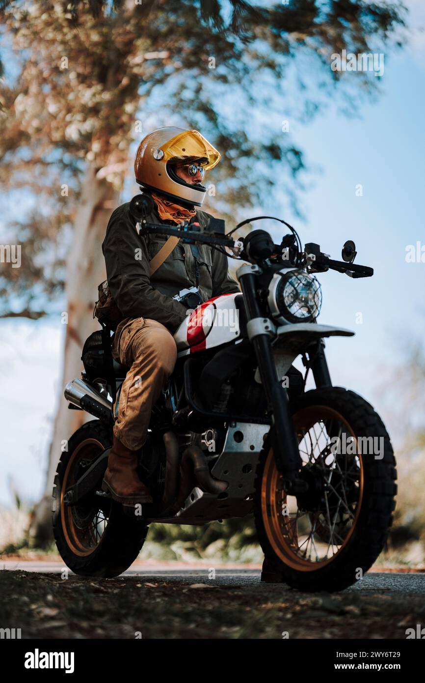Man riding motorcycle on road beside tree and bush Stock Photo - Alamy