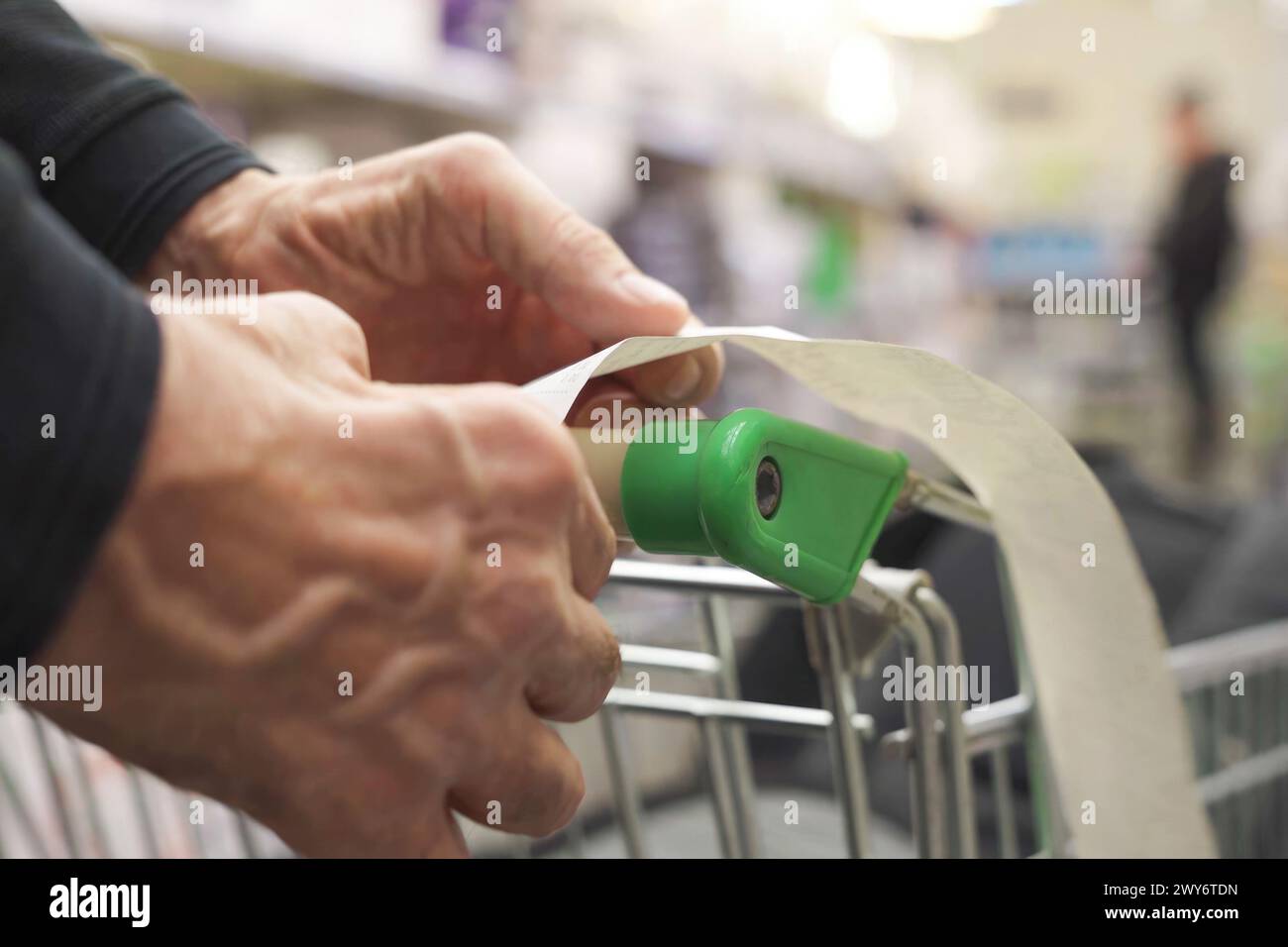 The hands of an unrecognizable older man hold a sales receipt next to a ...