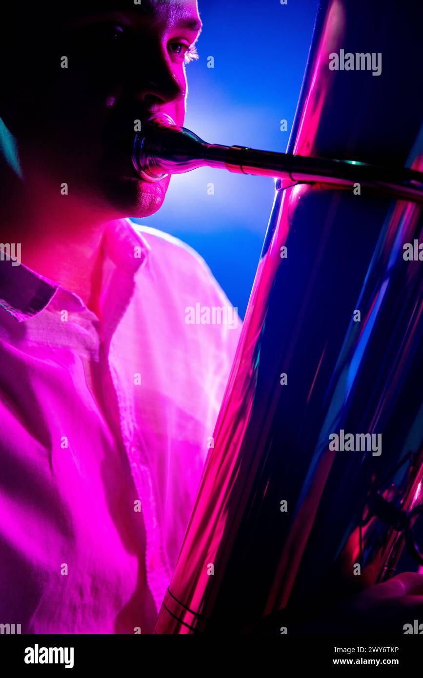 Portrait of talented musician seated, playing trumpet with soft blue ...