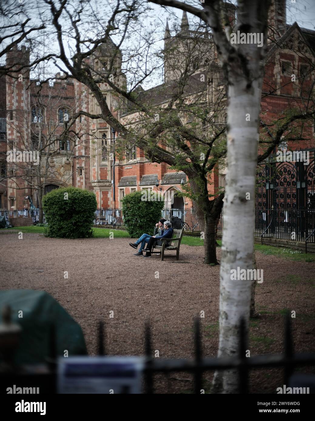 People sitting in the College Grounds on a park bench at Cambridge ...