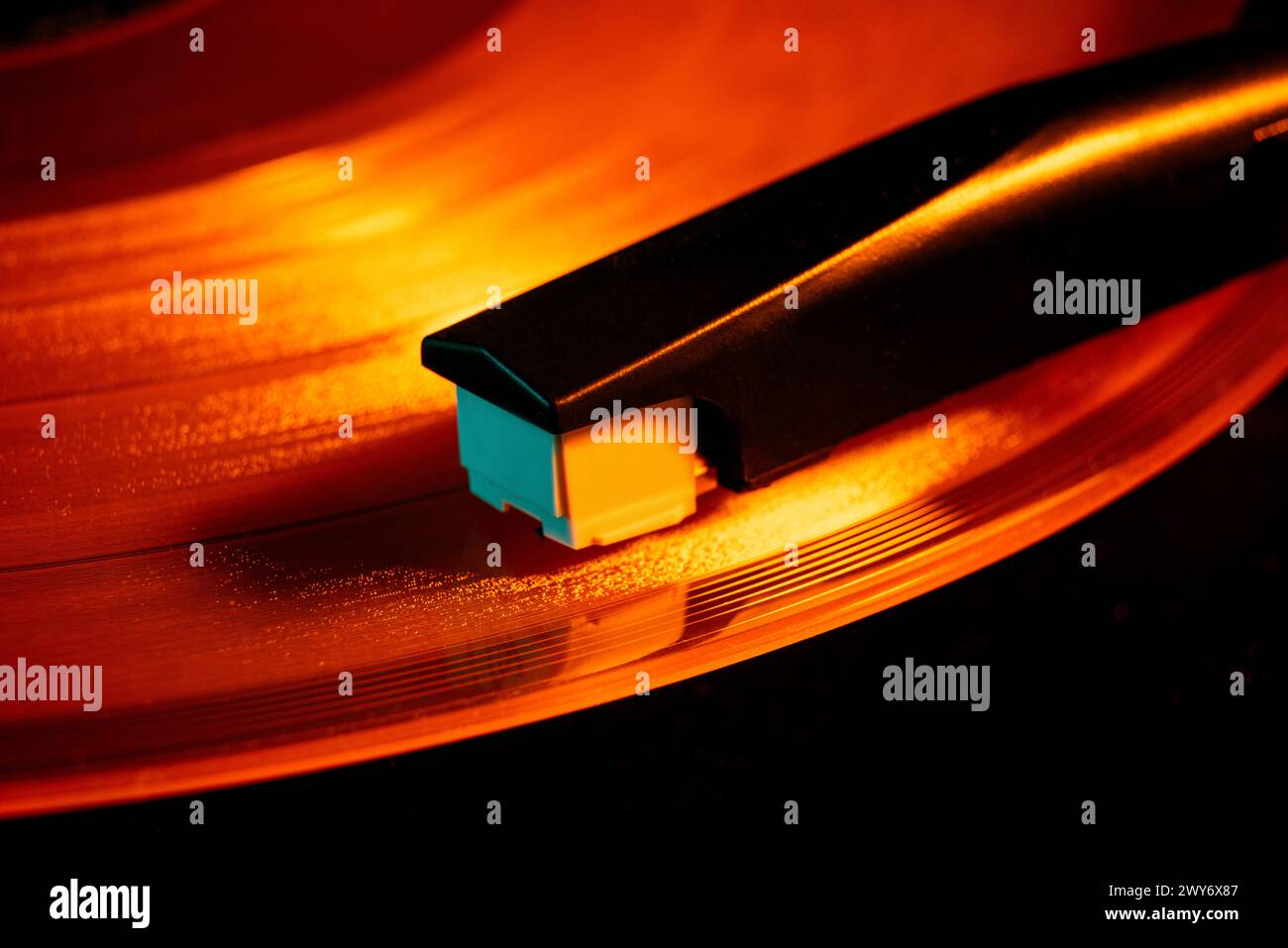 Close-up photo of turntable needle on vinyl record with warm orange ...