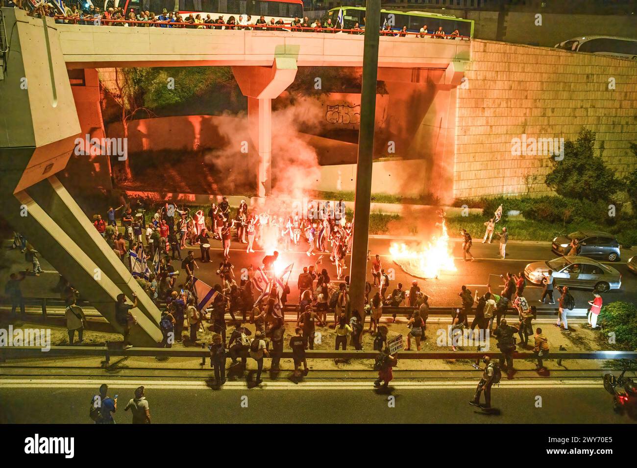 Protestors light up a torch and a bonfire in front of the blocked cars ...
