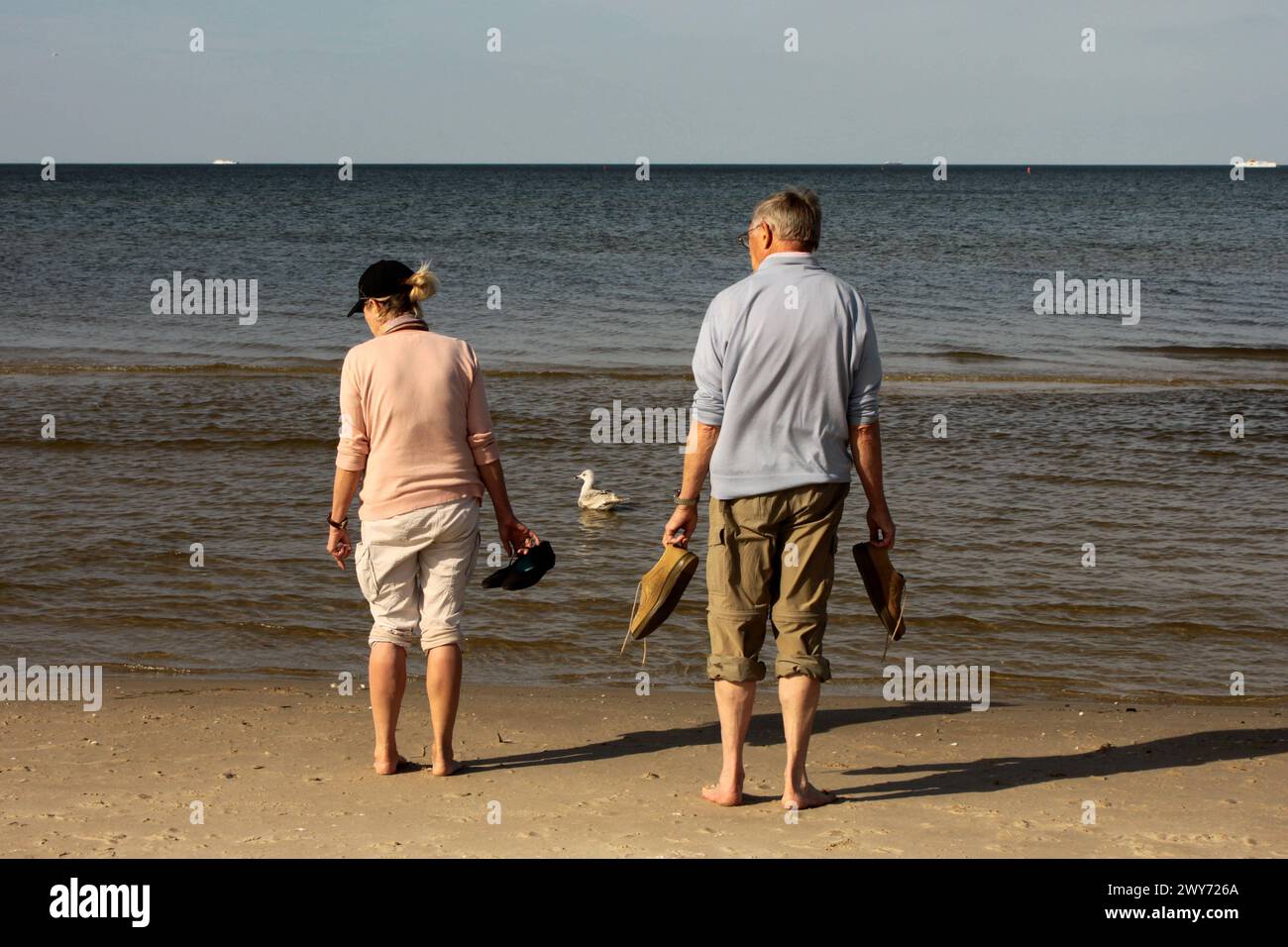 Personen gehen am Strand von Ahlbeck an der Ostsee barfuß durch den ...