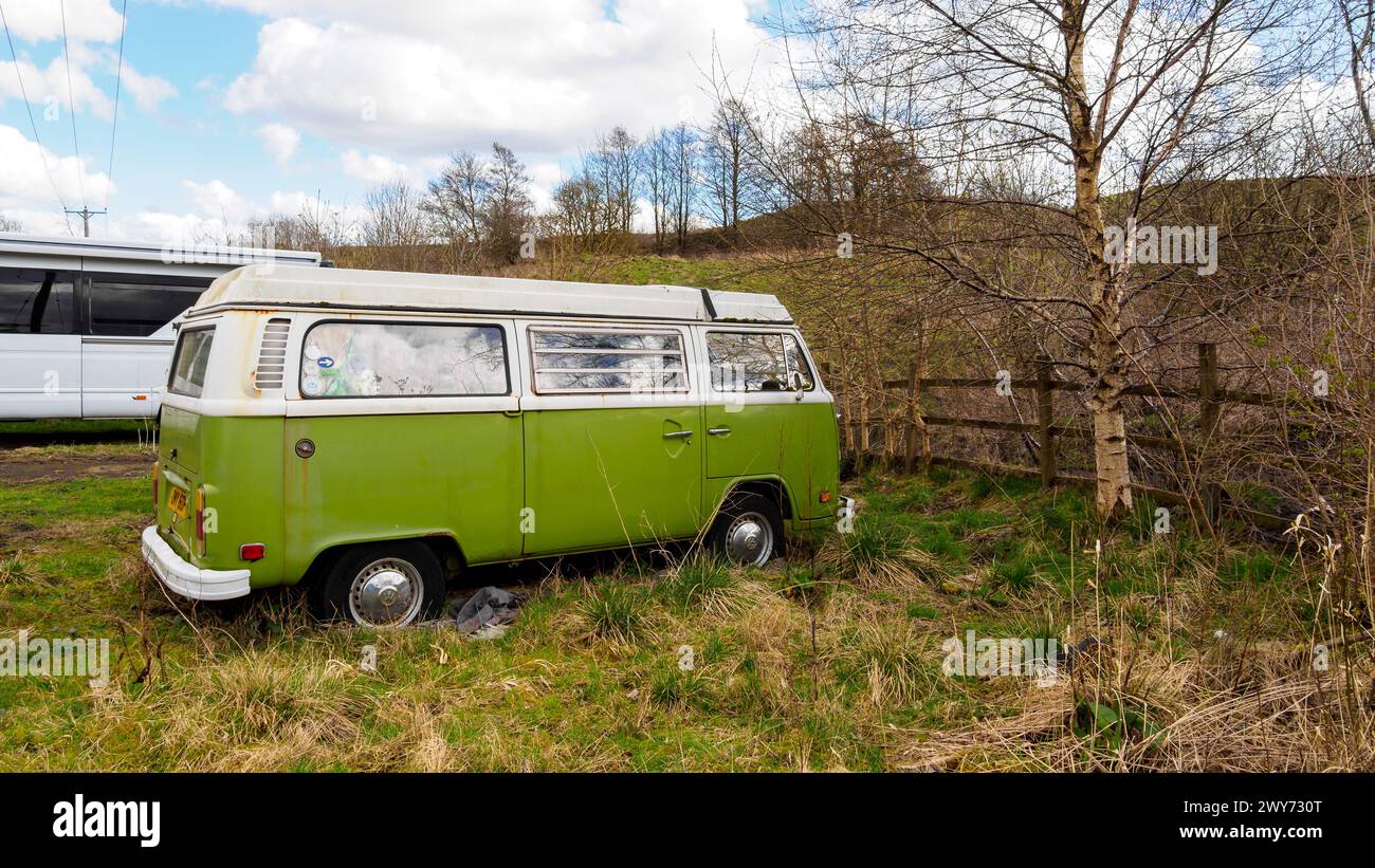 Old classic camper van left in a grassy field green Stock Photo - Alamy