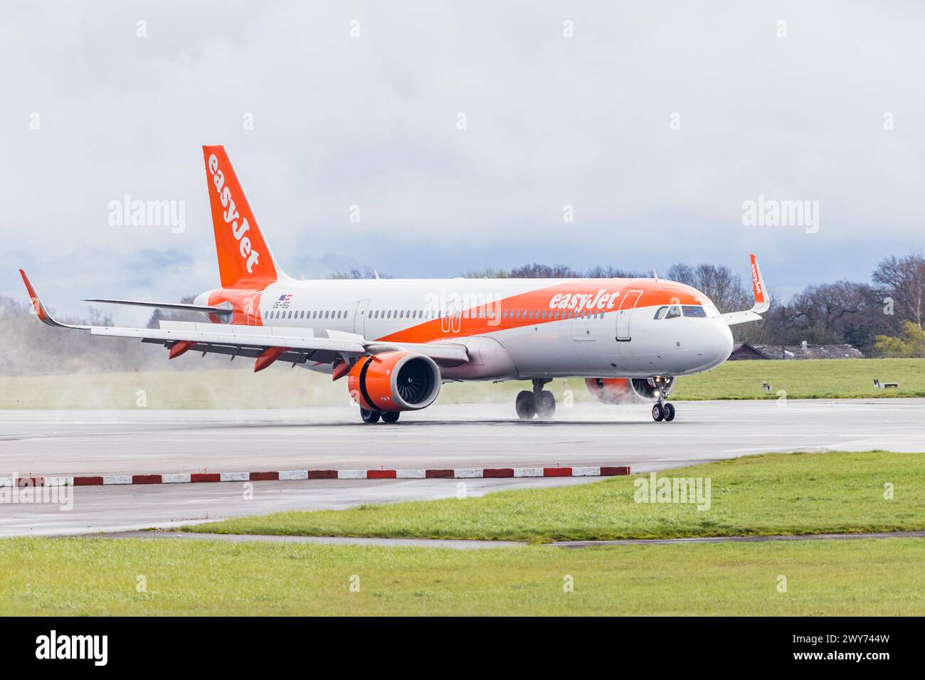 An EasyJet Airbus A320 slows on the runway creating spray behind it at ...