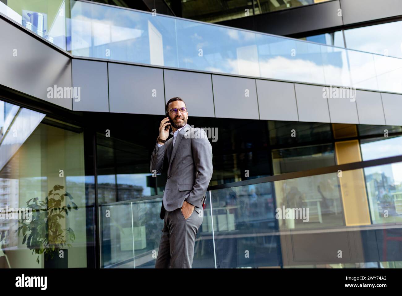 Suited man with arms crossed stands proudly before a sleek building ...