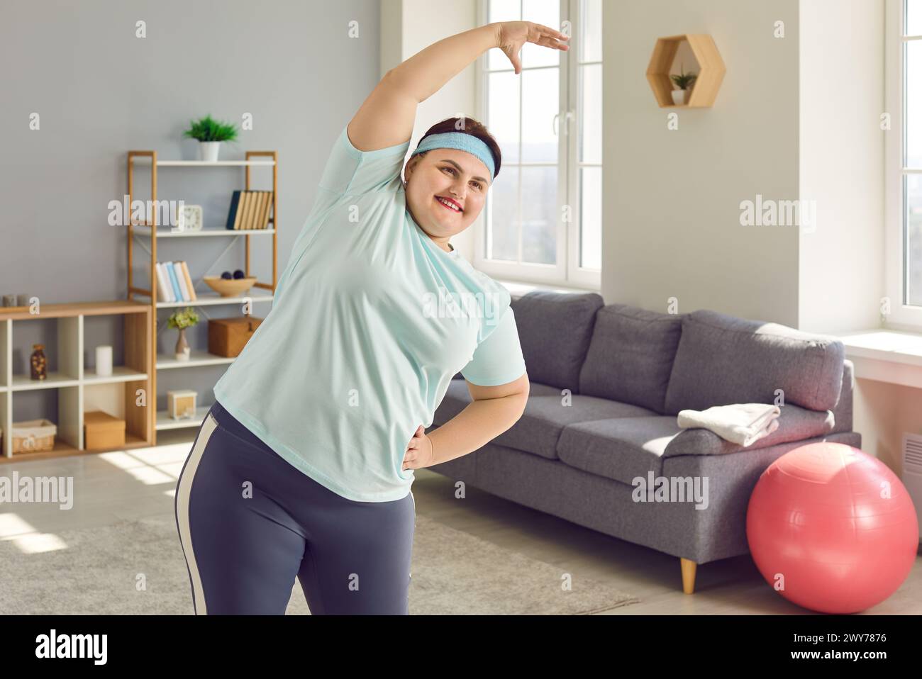 Portrait of a funny fat woman doing sport fit warm up exercises with ...