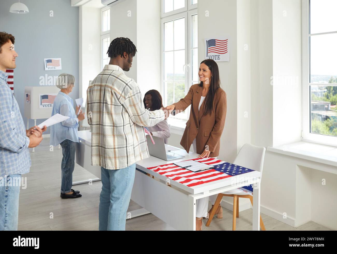 Man registering at polling station and shaking hands with woman ...