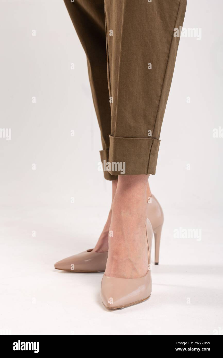 Fashion model posing in khaki pants and beige high heels. Isolated on a ...