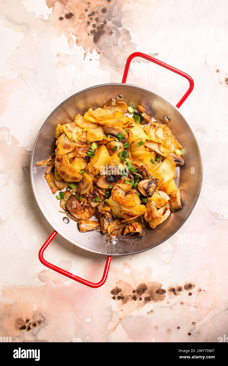 Sliced potatoes, fresh mushrooms, and diced onions sizzling in a frying ...