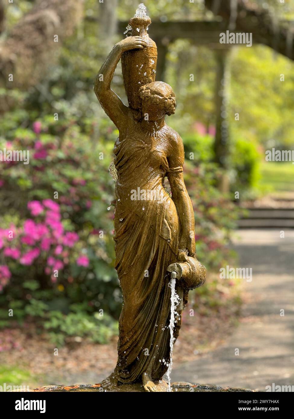 A woman sculpture holds a vase in a small fountain filled with water ...