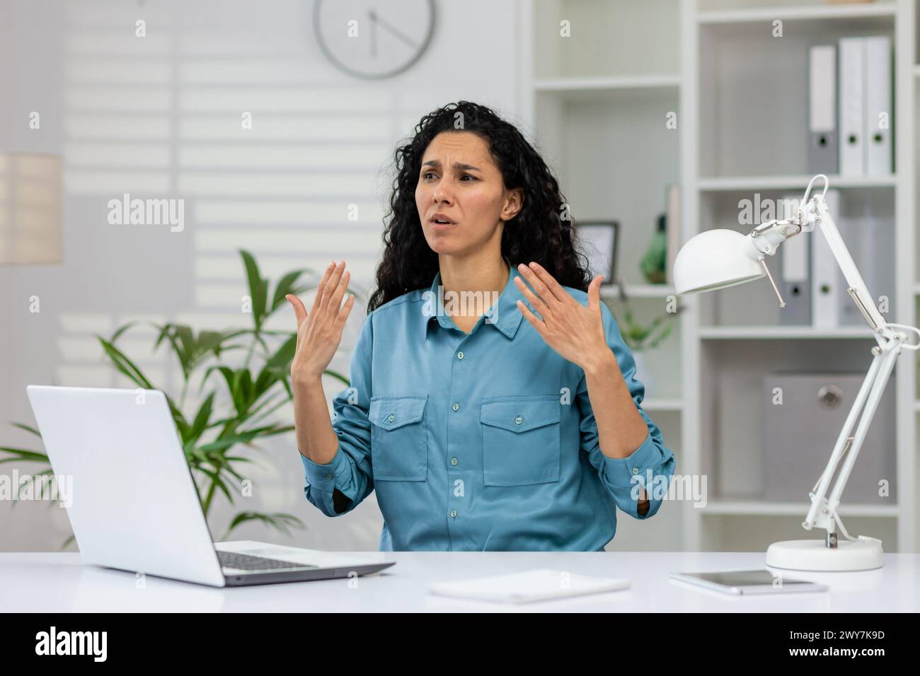 An uncomfortable businesswoman feeling too hot in an office setting ...