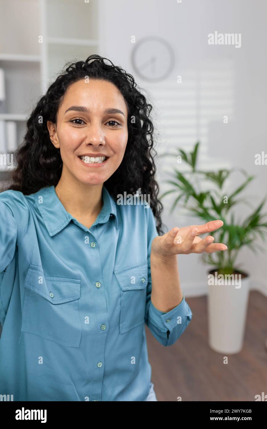 Confident professional in a blue shirt gesturing with an open hand ...