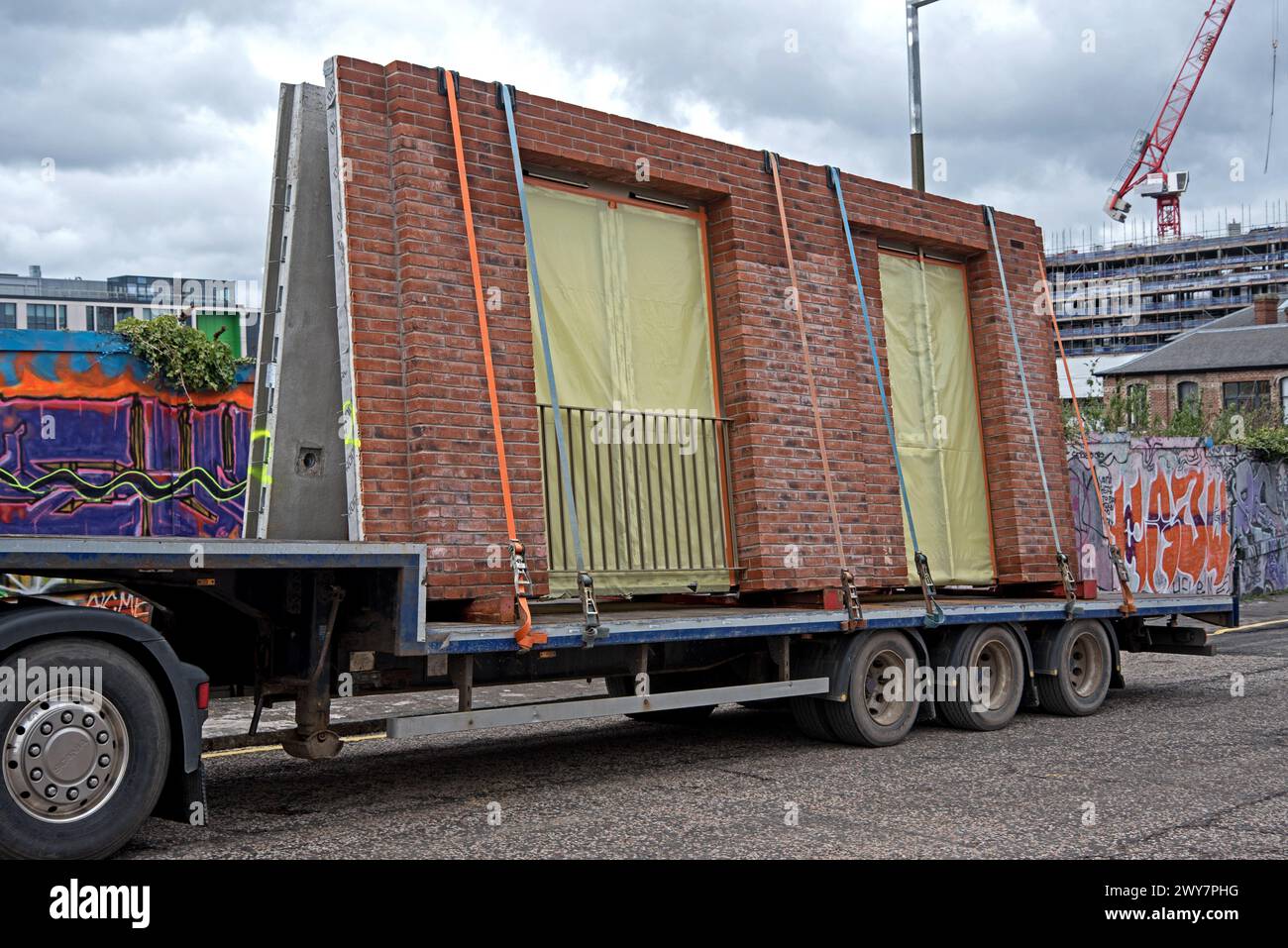 Precast concrete and red brick walls on a trailer arriving at a ...