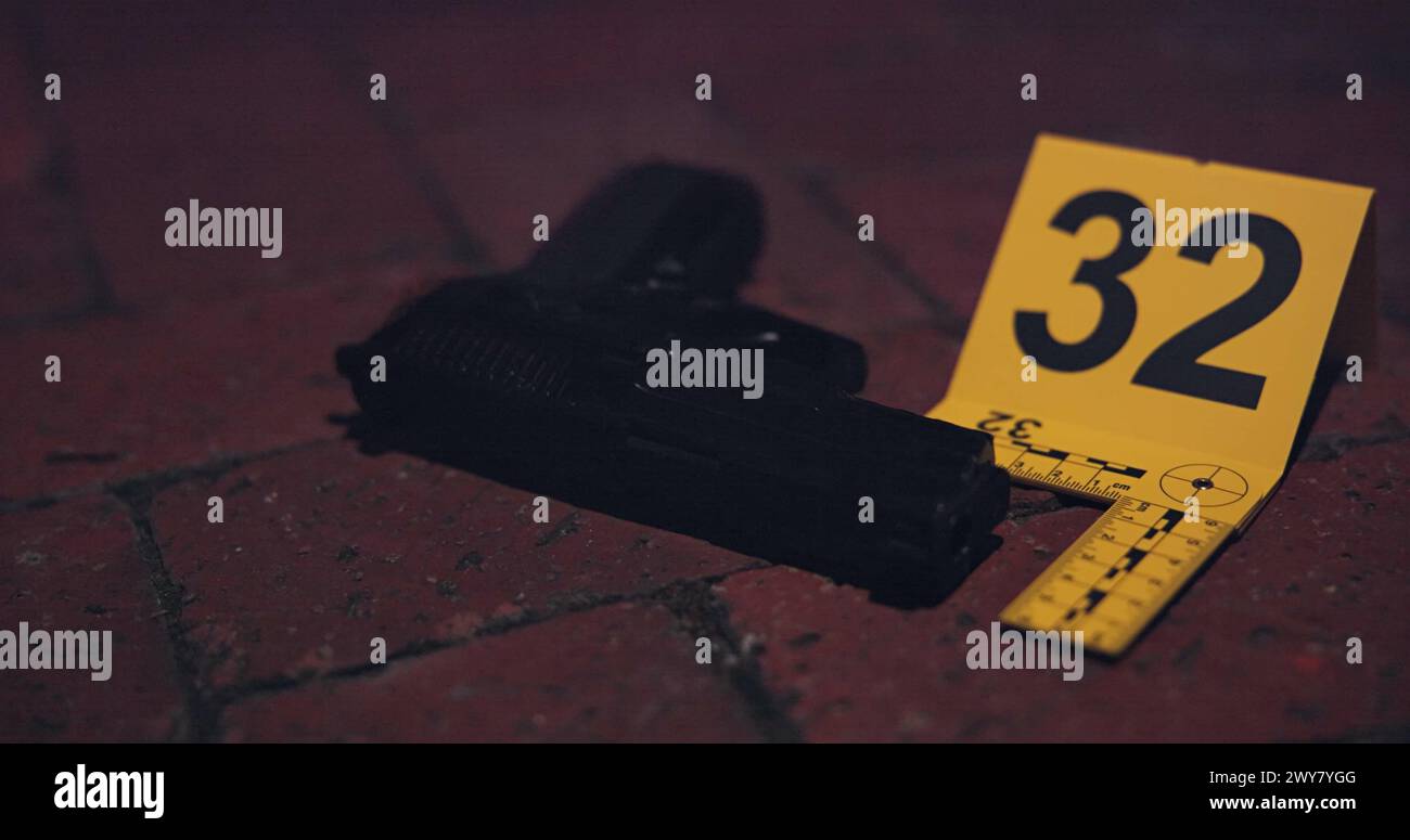 Gun, evidence and sign at crime scene in street with homicide, danger and investigation in ...