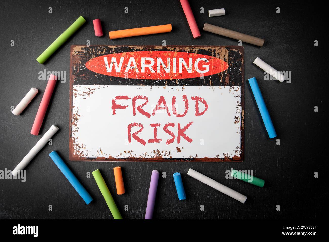 Fraud Risk. Metal warning sign and colored pieces of chalk on a dark ...