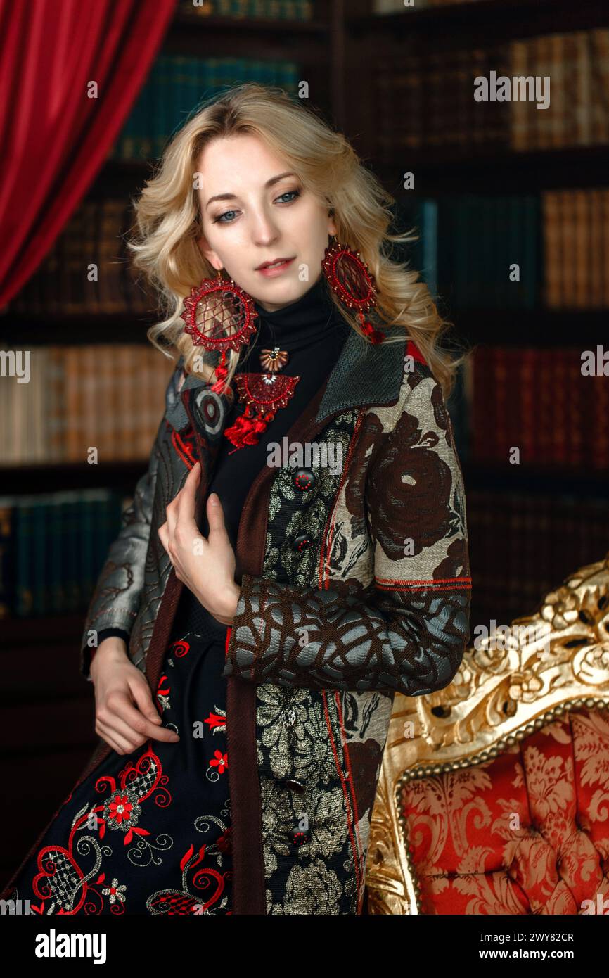 A woman stands confidently in front of a bold red chair, creating a ...