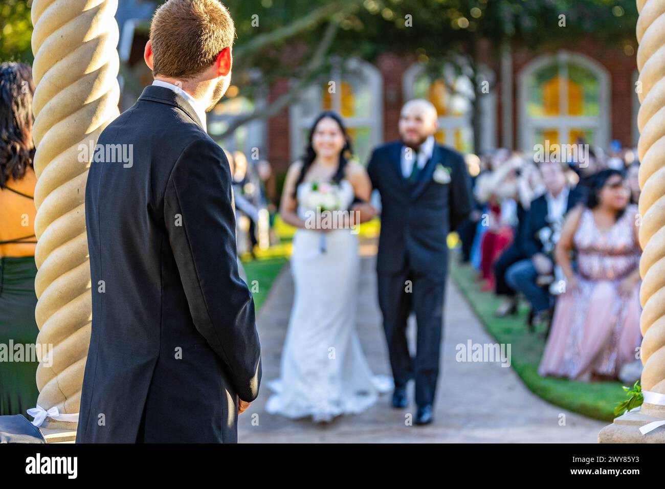 Guests facing newlyweds as a man approaches Stock Photo - Alamy