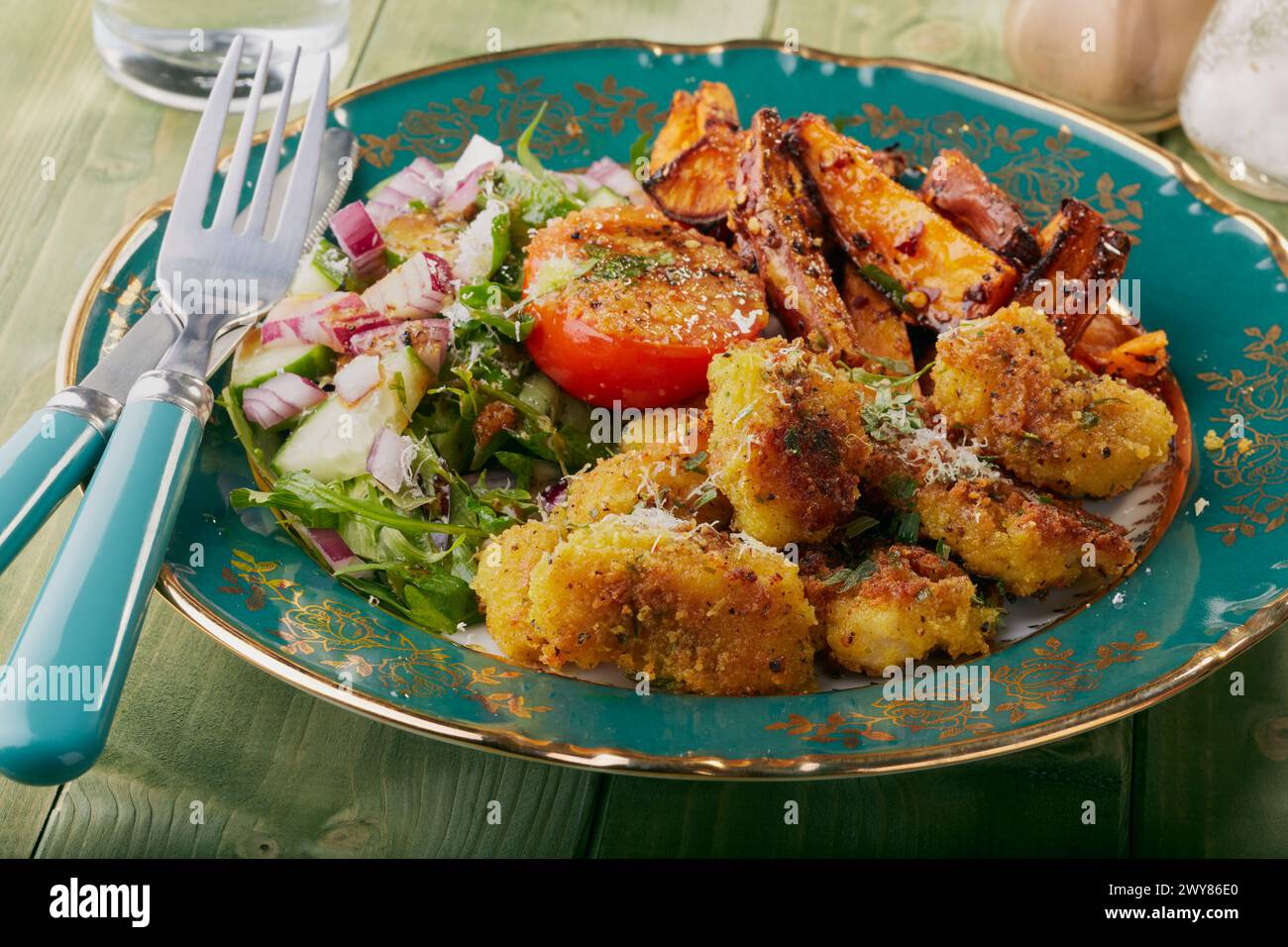 Breaded fish bites with chili potato wedges and a mixed salad Stock ...