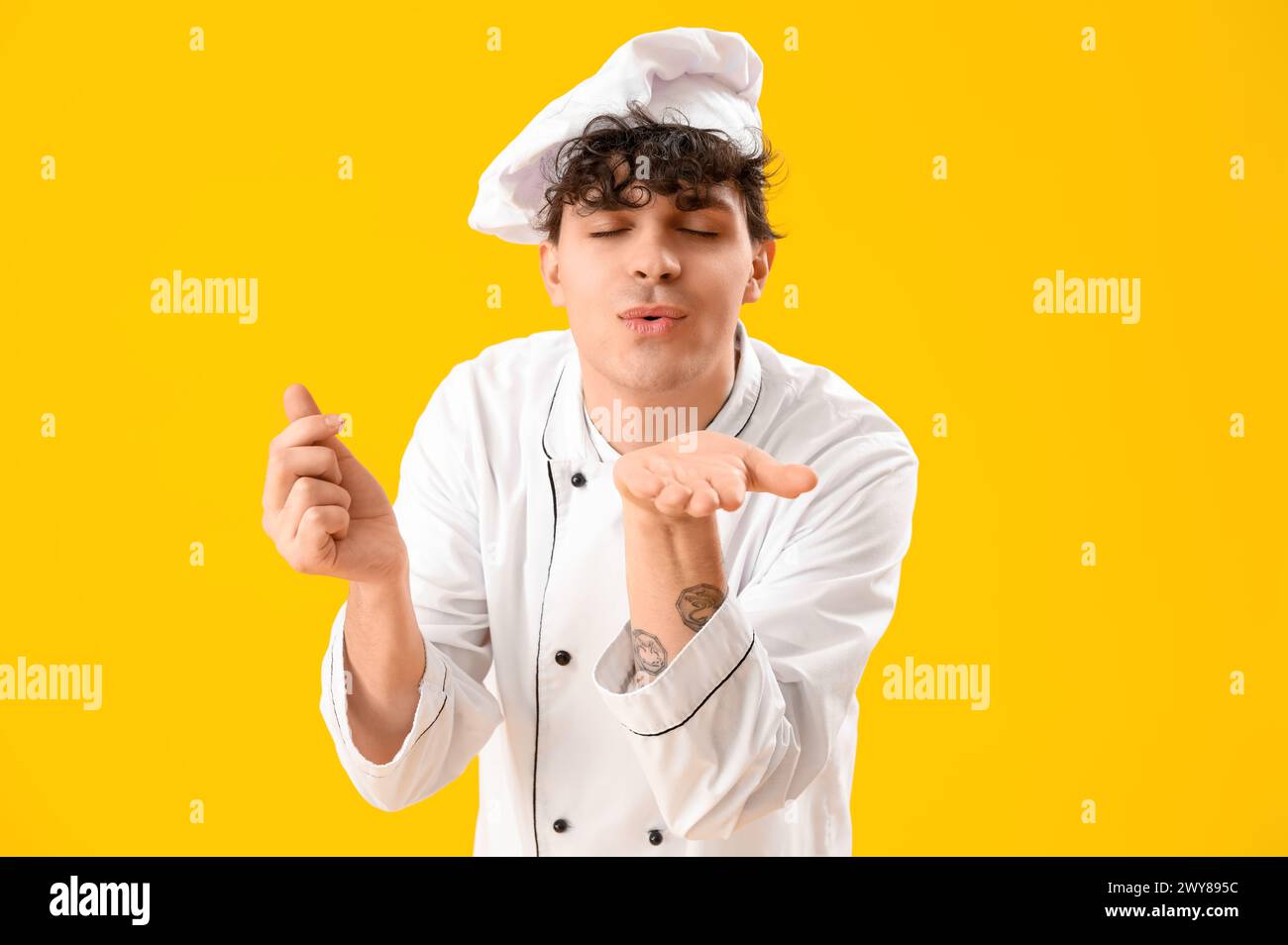Male chef blowing kiss on yellow background Stock Photo - Alamy