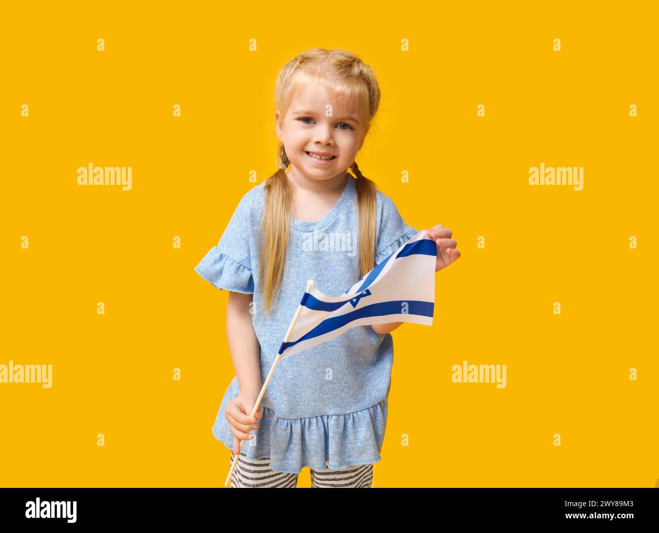 Cute happy little girl with Israel flag on yellow background. Hanukkah ...