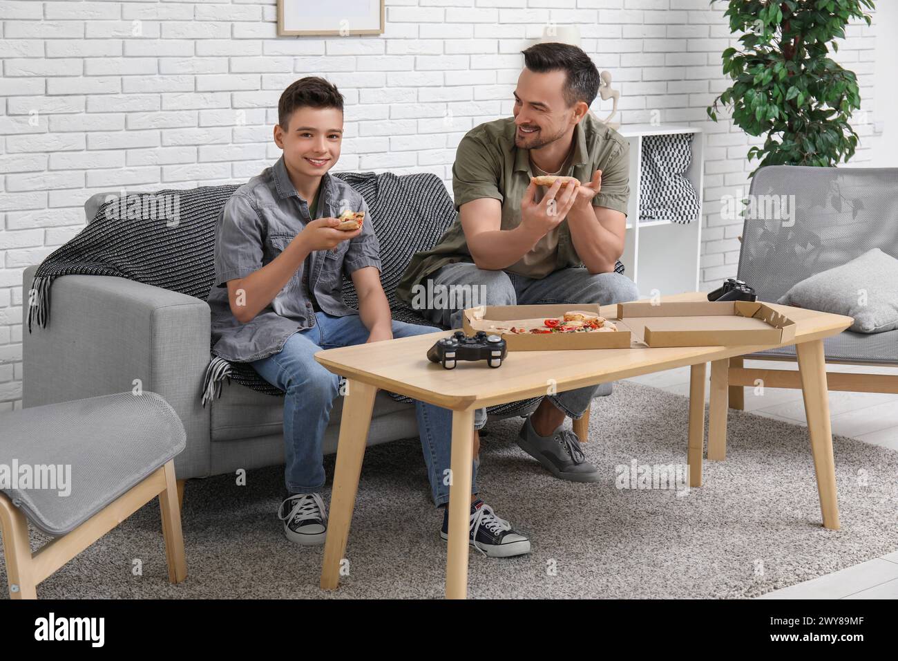 Father and his little son eating pizza at home Stock Photo - Alamy