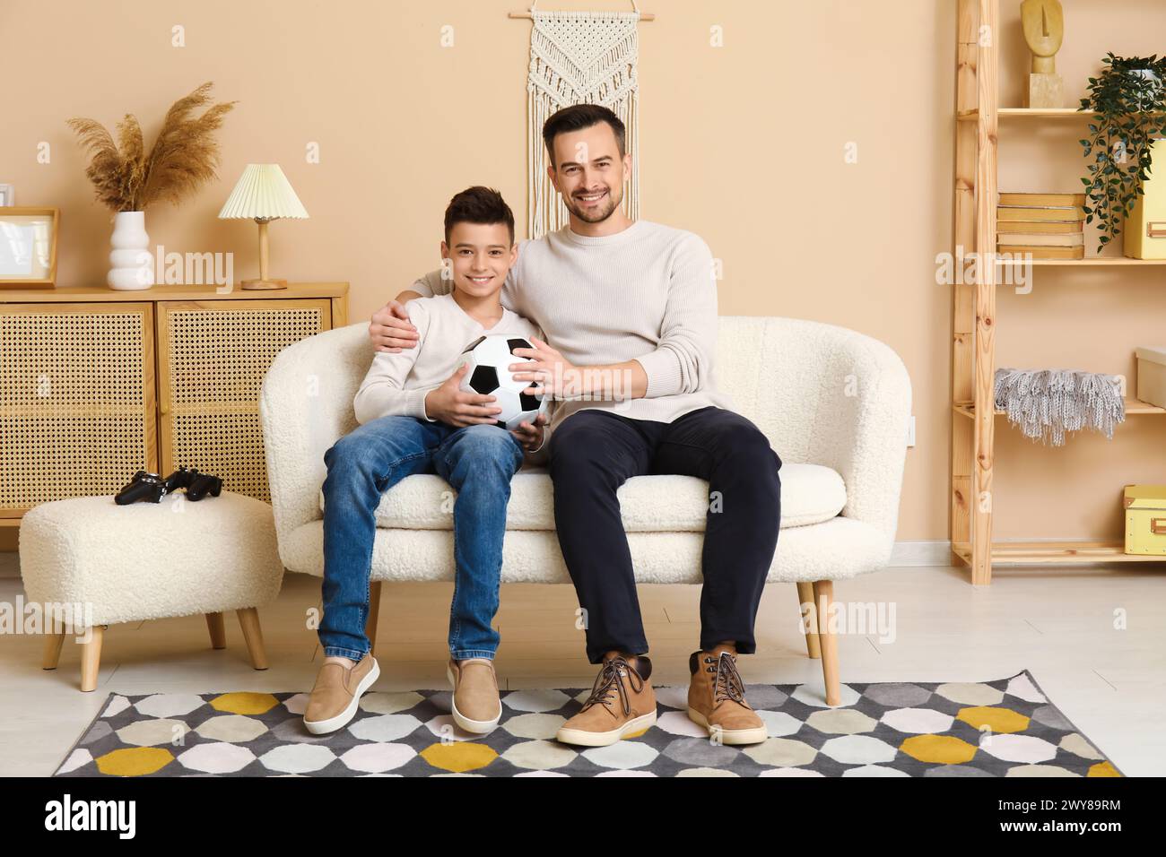 Happy father and his little son with soccer ball on sofa at home Stock ...