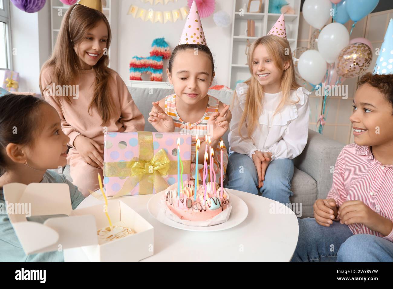 Cute little girl with her friends making wish at Birthday party Stock ...