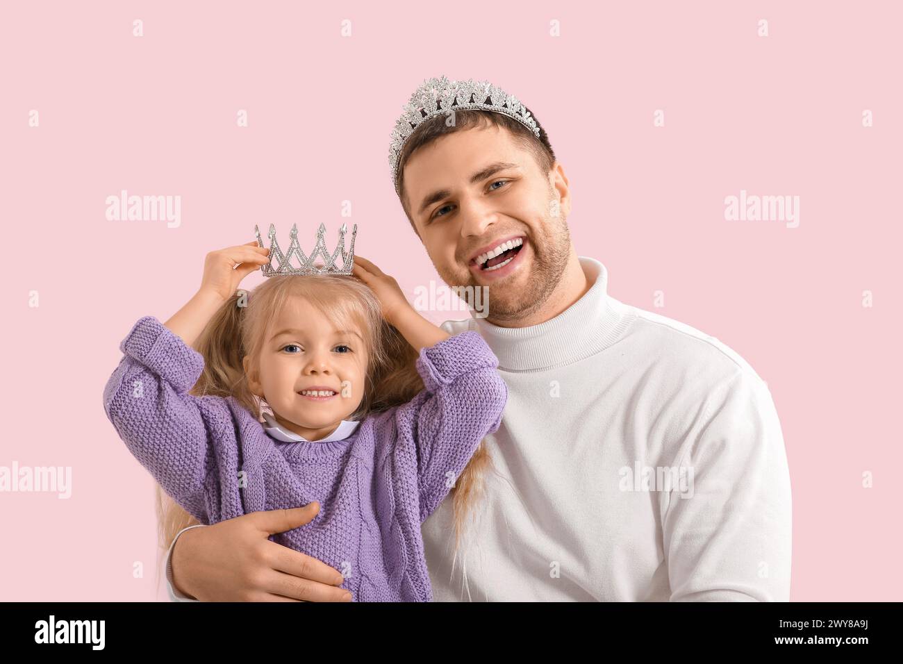 Happy father and his cute little daughter in princess crowns on pink background Stock Photo - Alamy