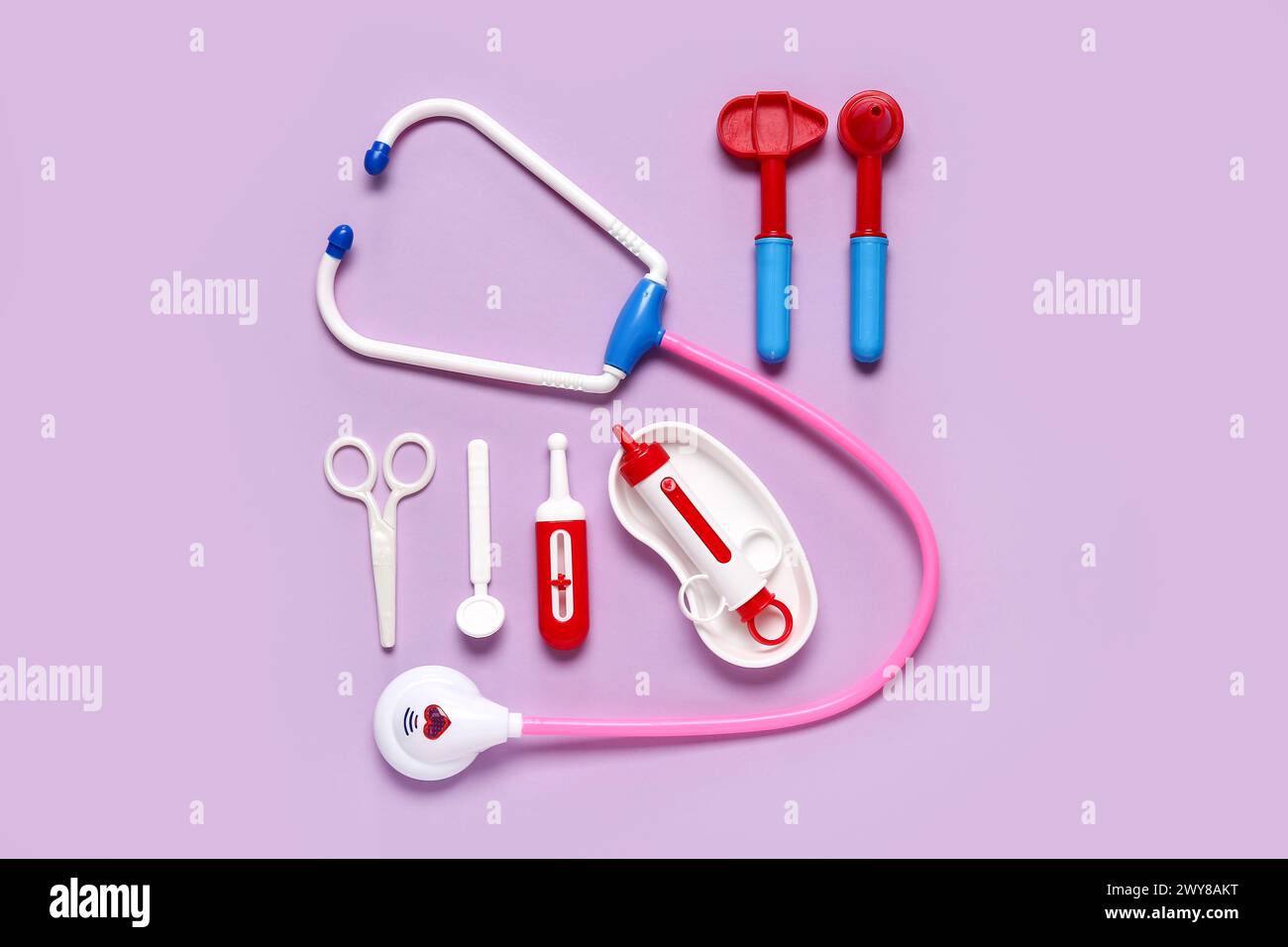Toy stethoscope with injection and reflex hammer on lilac background ...
