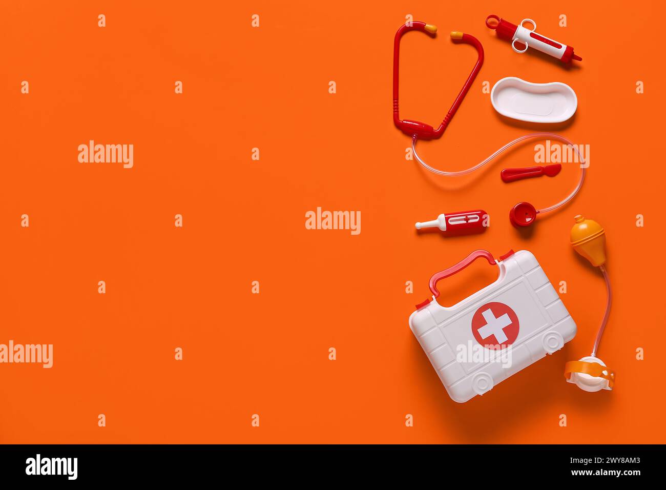 Toy first aid kit with stethoscope and thermometer on orange background ...